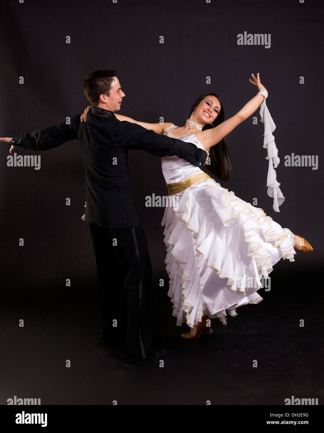 Young ballroom dancers in formal costumes posing against a solid ...