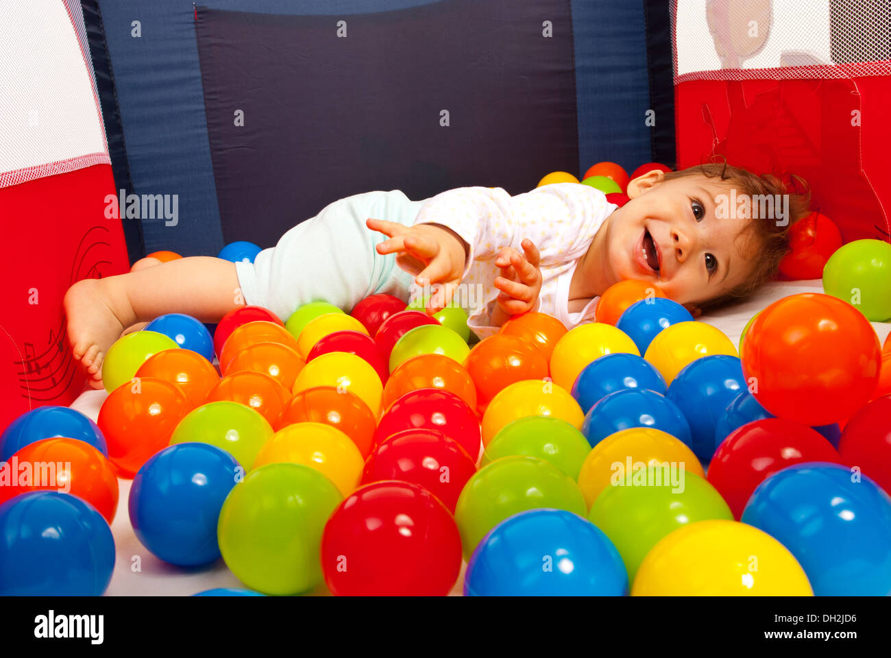 Happy baby playing with balls inside playpen Stock Photo - Alamy