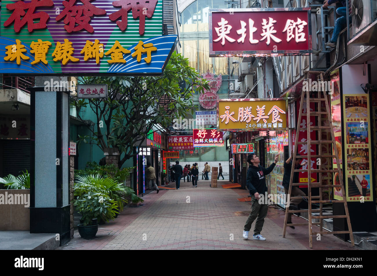 Men hanging advertisements in Macau, China Stock Photo - Alamy