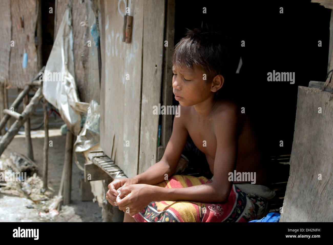 A child laborer boy who works in the recycling industry is sitting in ...