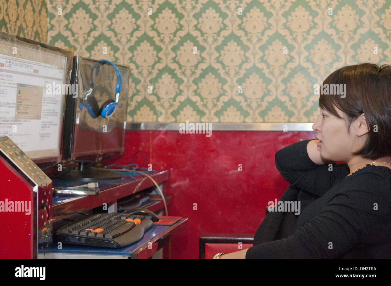 A young Chinese woman an internet cafe, or cyberbar uses Skype on a ...