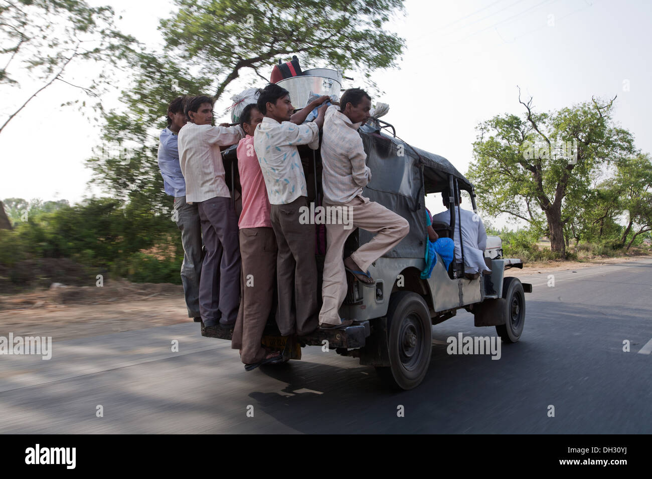 people crowded on a jeep taxi running on the road near New Delhi India ...