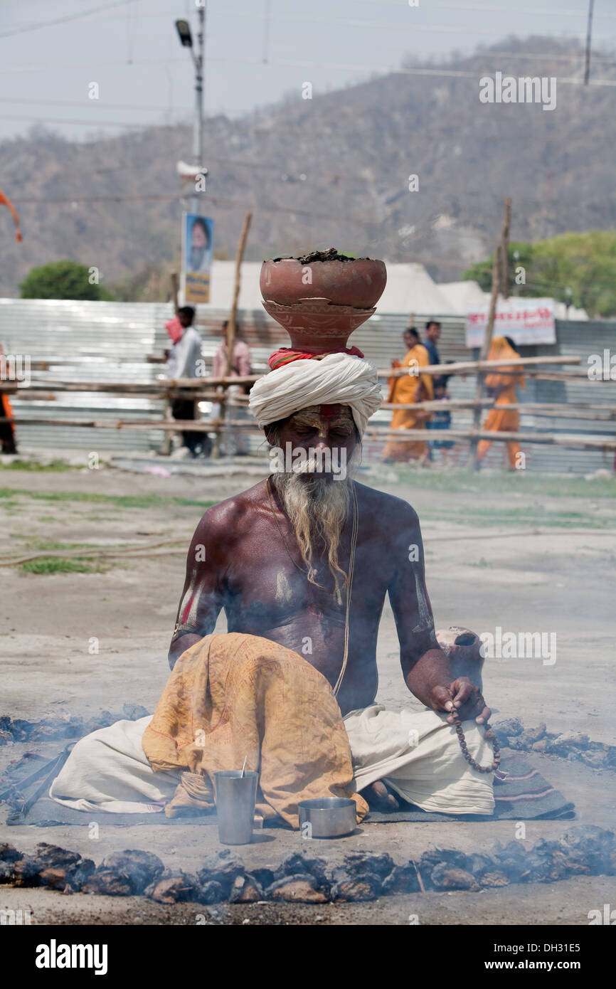 Sadhu doing penance pooja surrounded by burning coal and balancing ...
