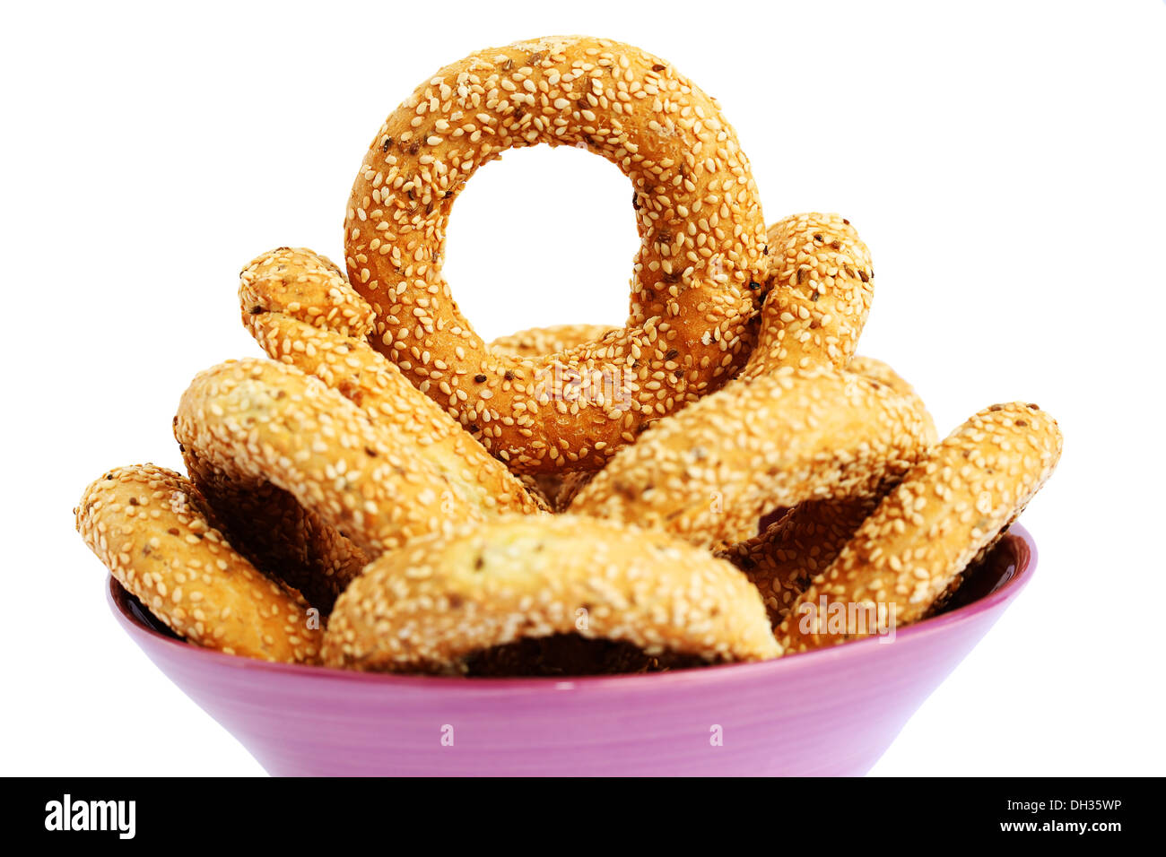 Round rusks with sesame seeds in pink bowl isolated on white background ...