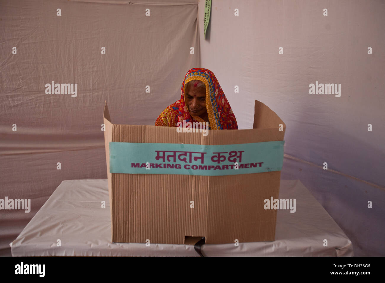 Indian woman voting in marking compartment of polling station for ...