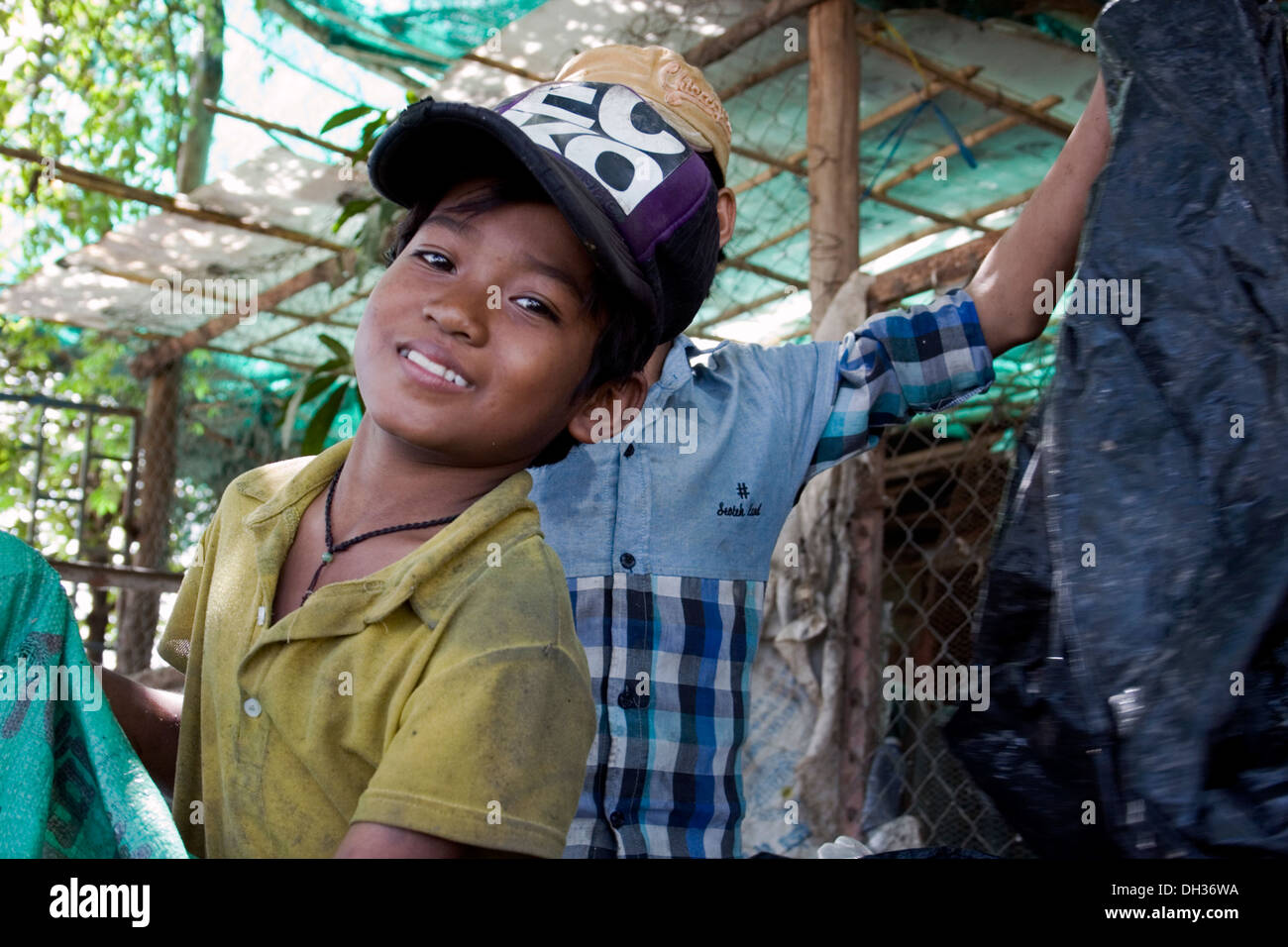 A child laborer boy is smiling as he works at a garbage recycling depot ...