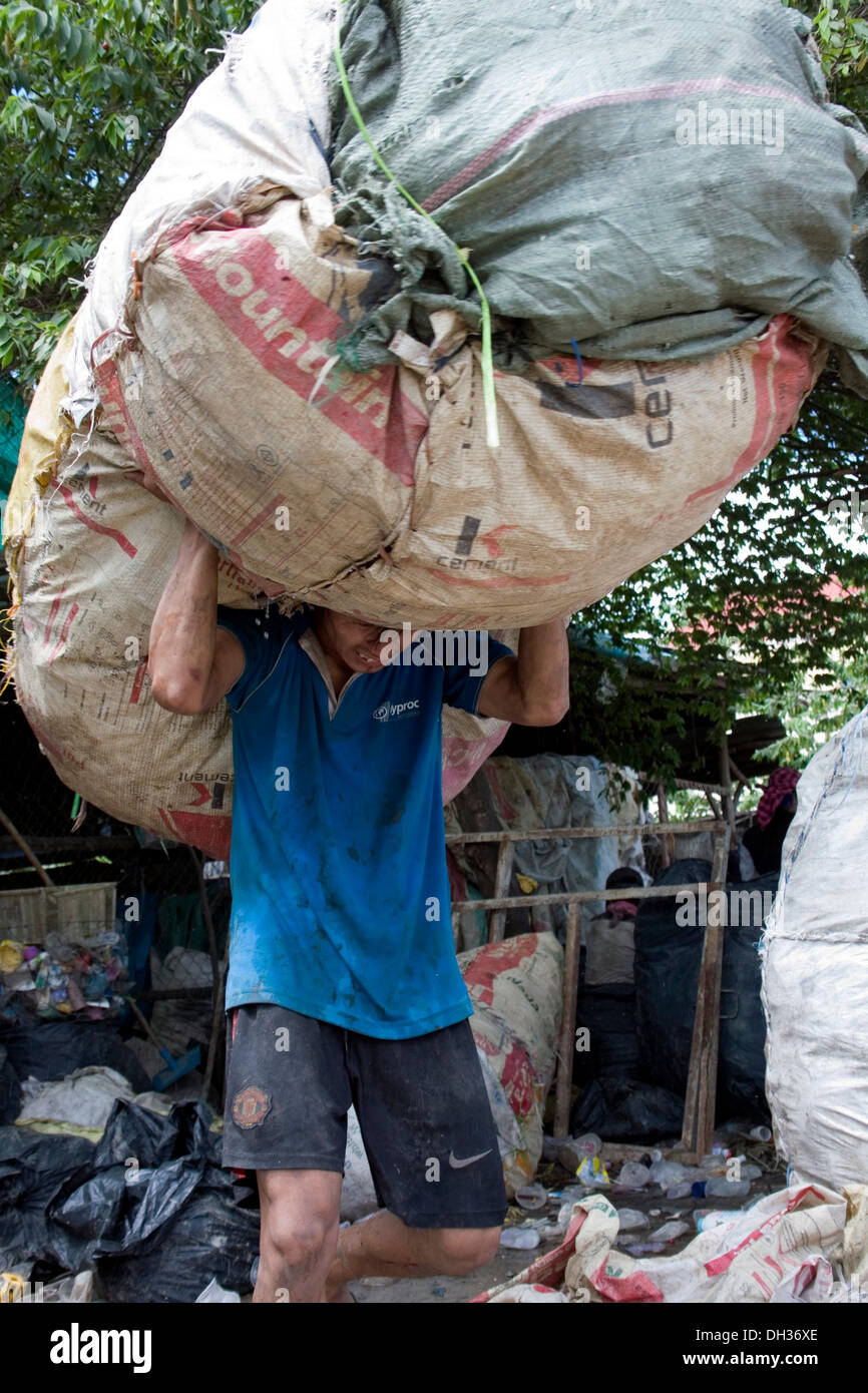 A young man is carrying a heavy sack filled with recyclable material at ...