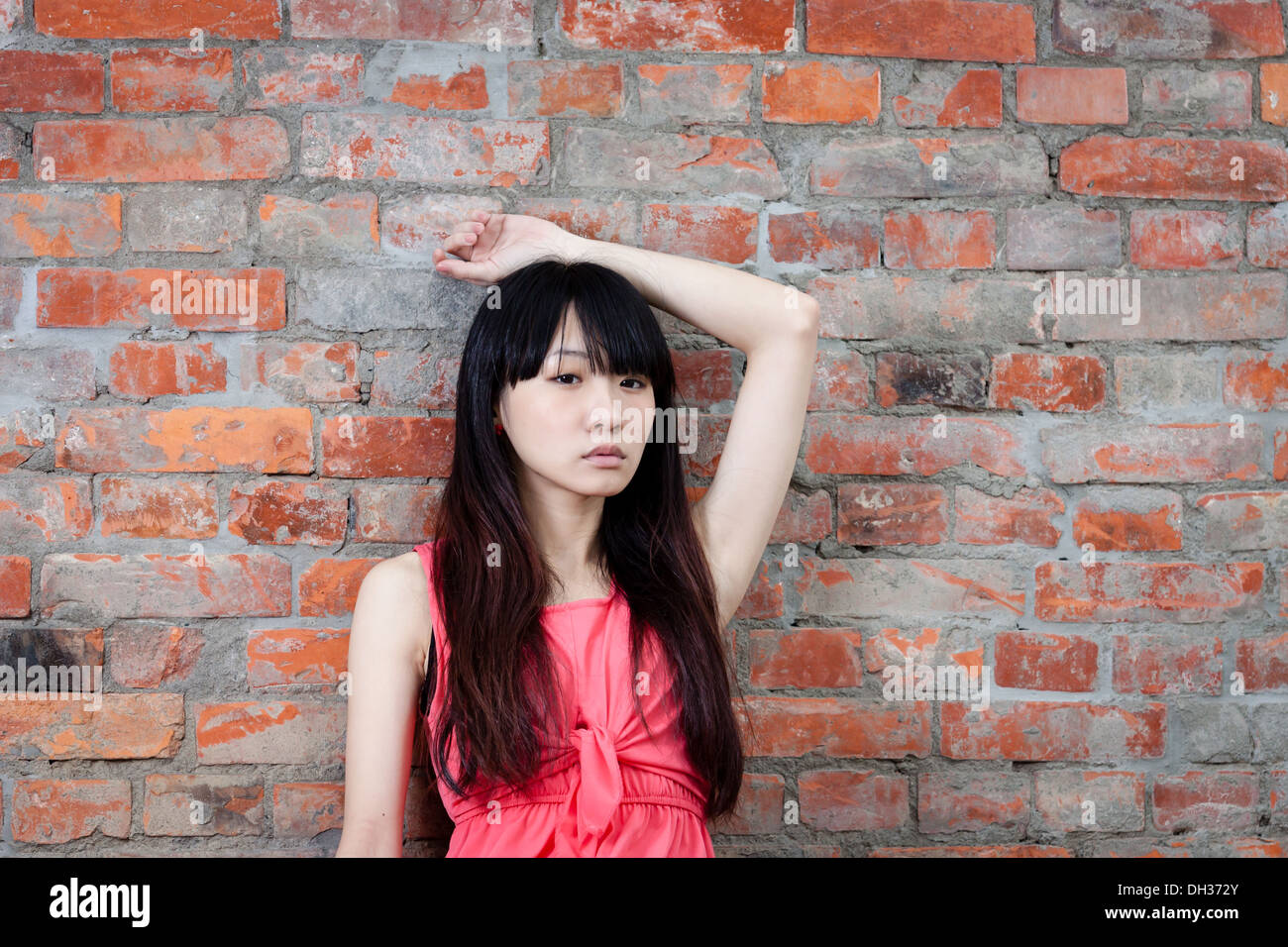 Chinese woman with sad expression by brick wall Stock Photo - Alamy