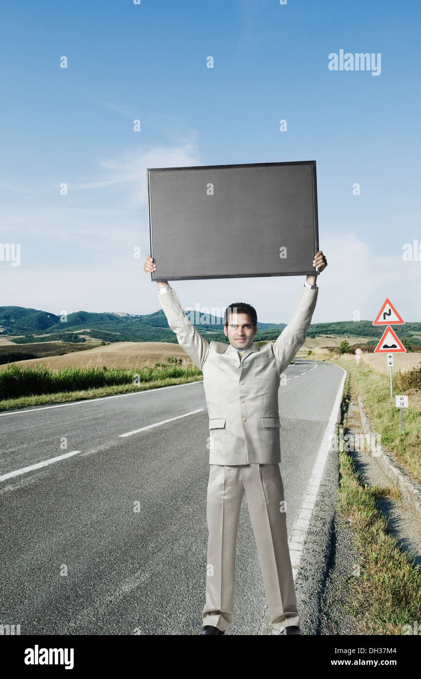 Businessman standing on the roadside and holding a sign Stock Photo - Alamy