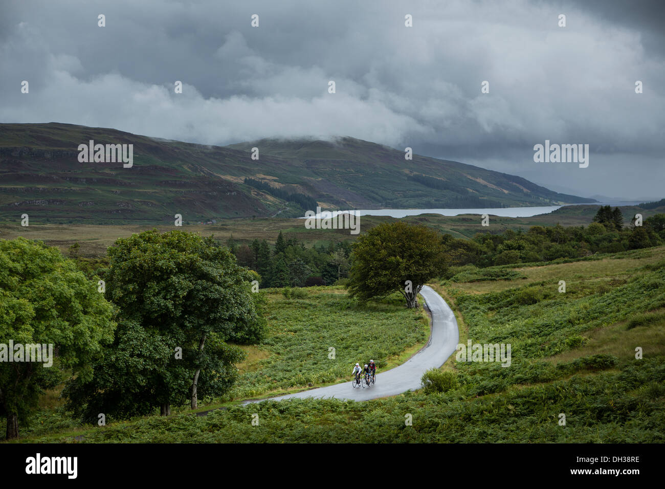 Three cyclists ride a wet path in the Scottish Highlands, Scotland ...