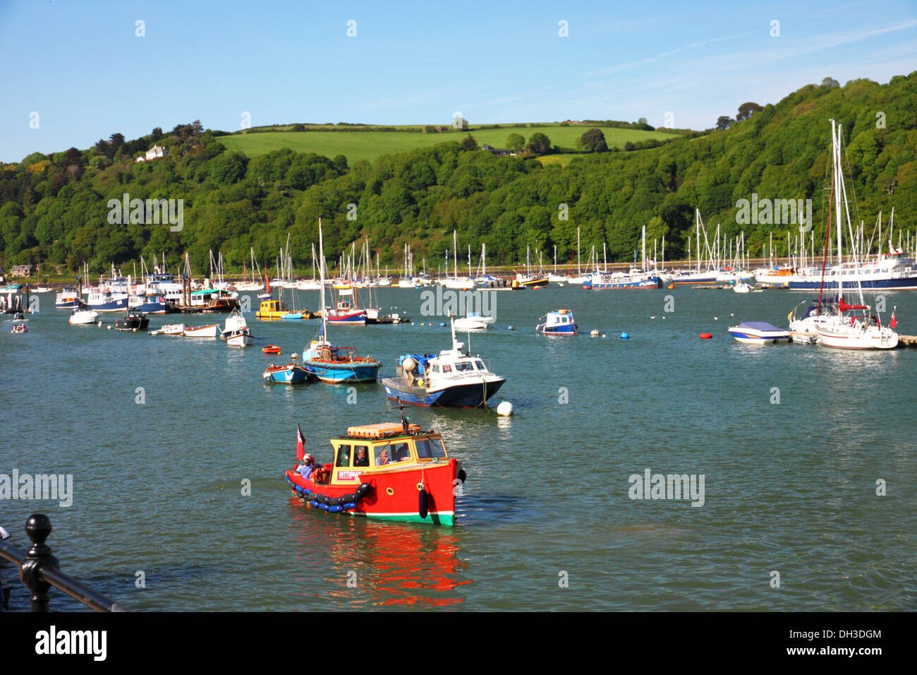 A red boat on a river with moored boats behind, tree-lined banks Stock ...