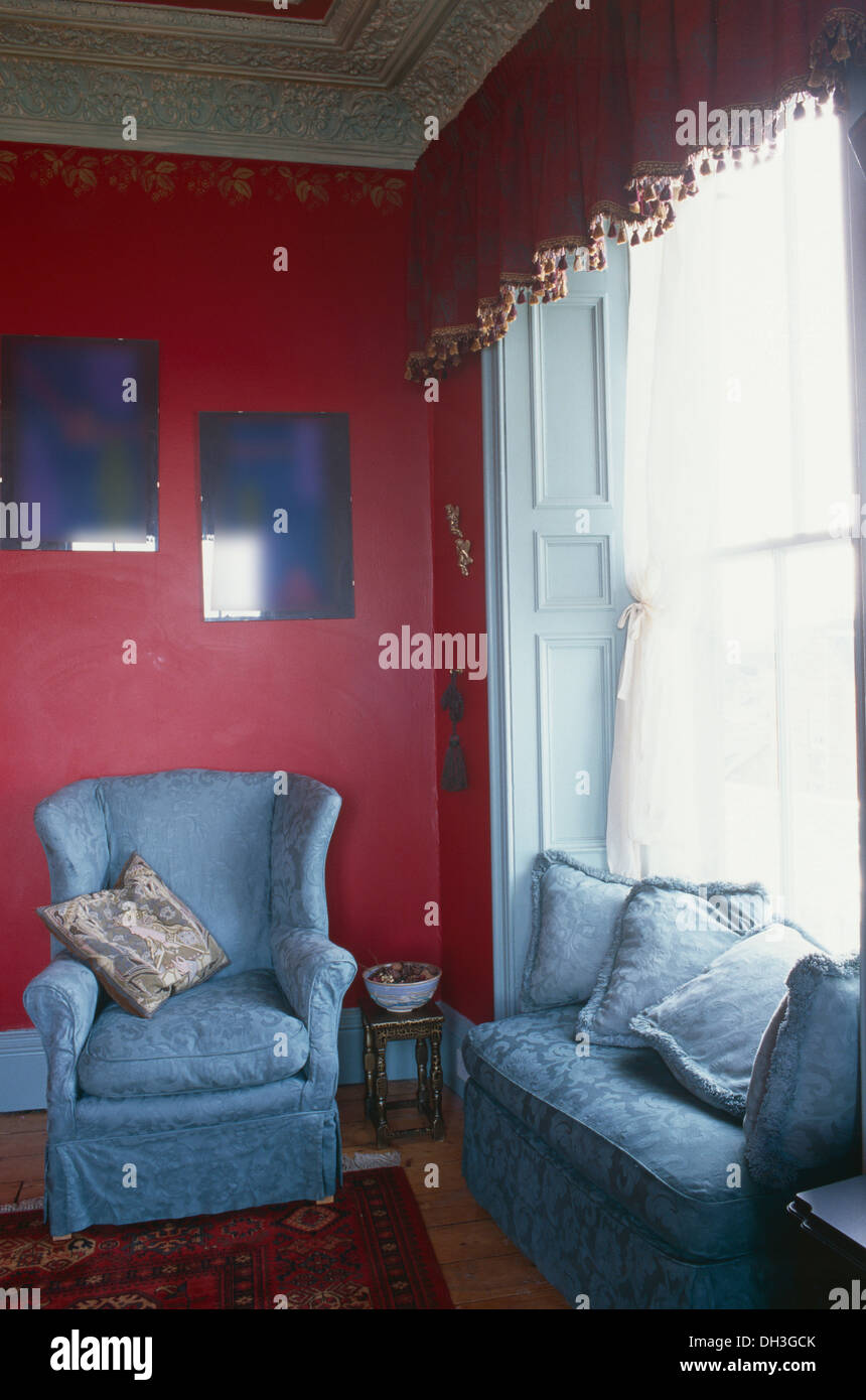 Ornate plaster cornice in red living room with blue armchair beside ...