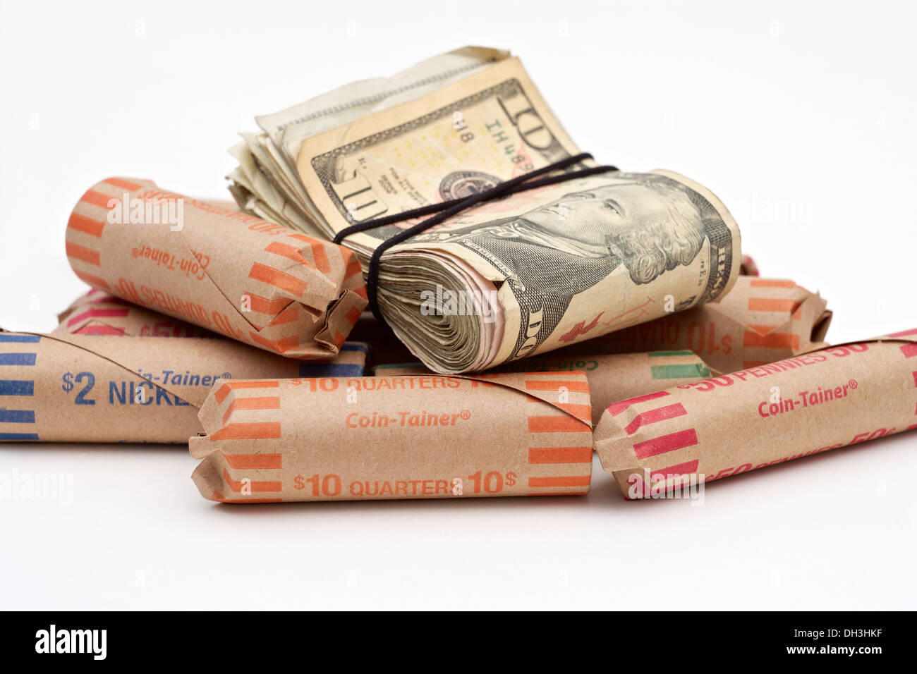 Folded and rubber banded wad of cash laying on top of a pile of rolled ...