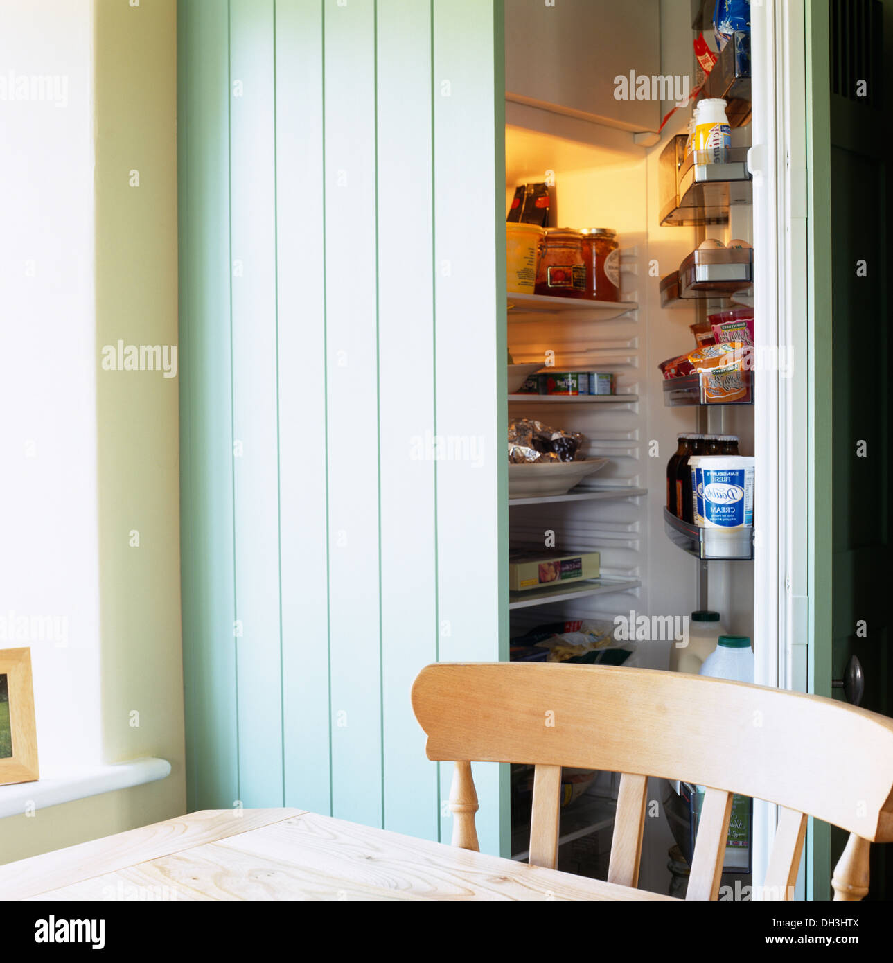 Pale wood chair at kitchen table in front of aqua blue open door to ...