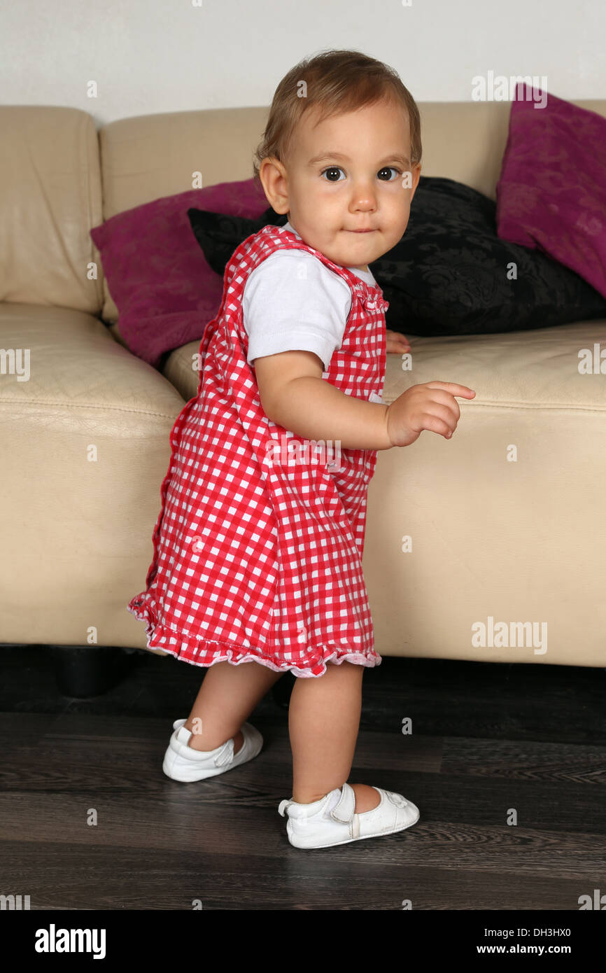 A small baby girl tries to walk, taking its first steps Stock Photo - Alamy