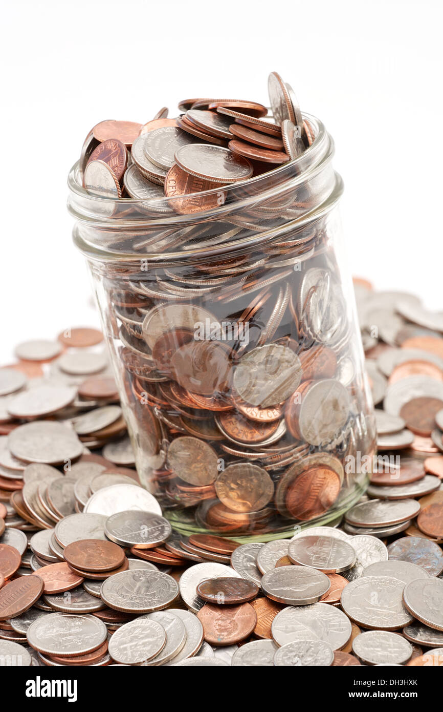 Glass mason jar full of loose pocket change spilling out on white ...