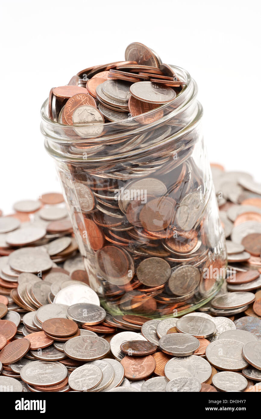 Glass mason jar full of loose pocket change spilling out on white ...