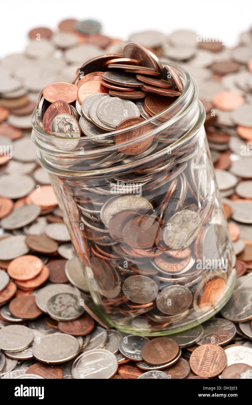 Glass mason jar full of loose pocket change spilling out on white ...