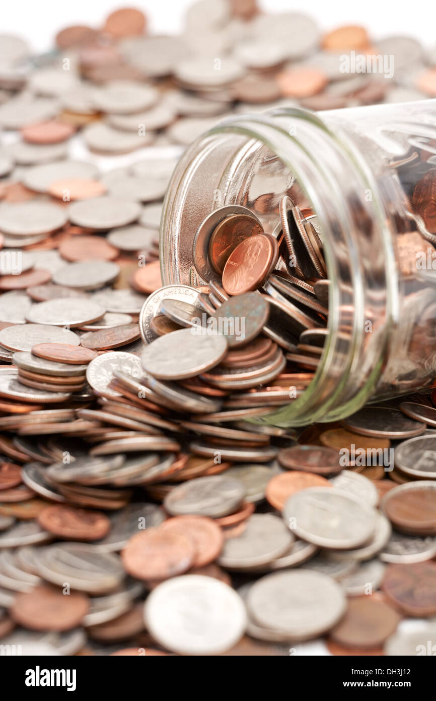 Glass mason jar full of loose pocket change spilling out on white ...