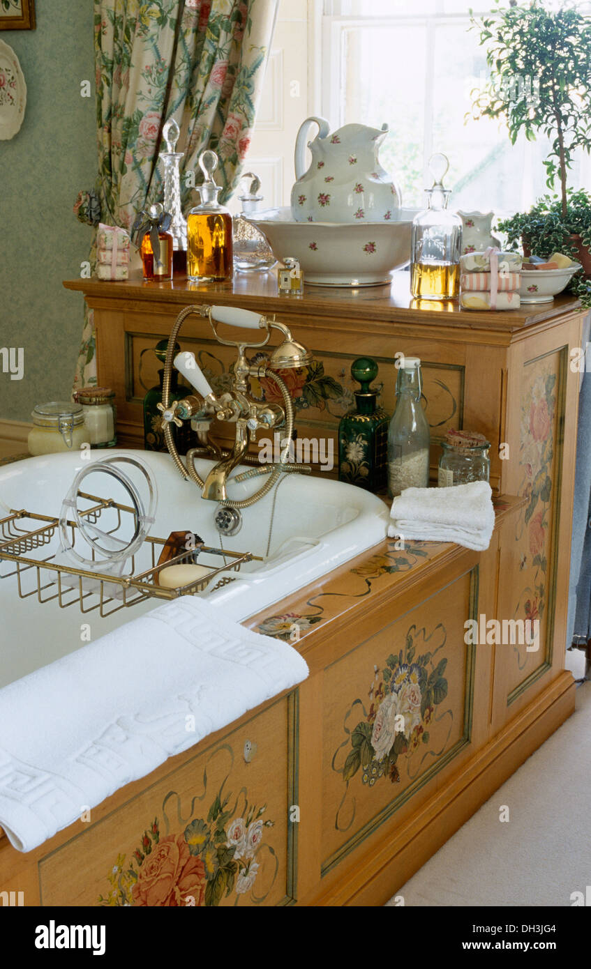 Brass bath rack and taps on roll top bath set in wooden surround with ...