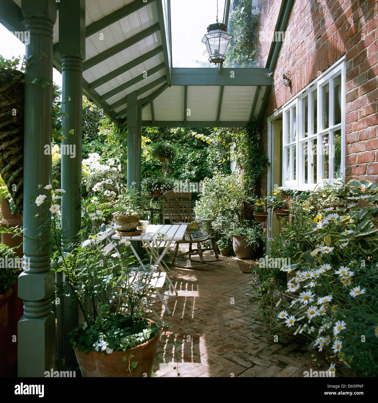 White daisies in pots on covered veranda with table and chair and ...