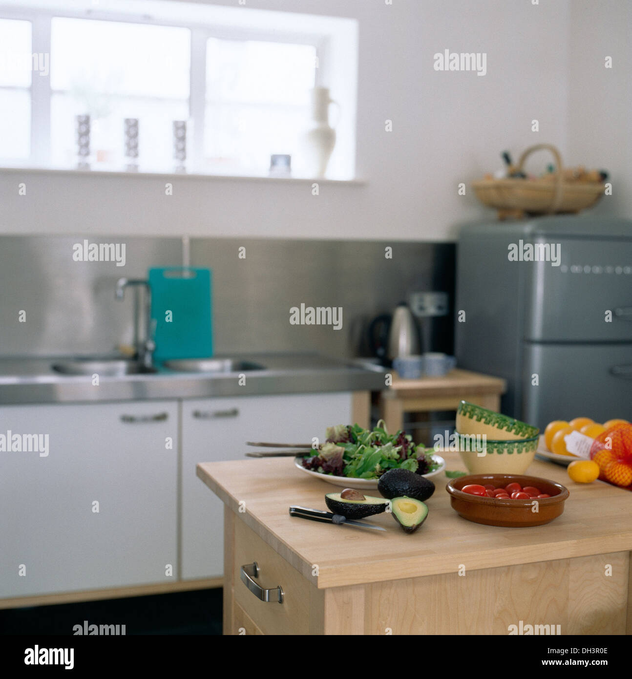 Bowls of salad and fruit on pale wood butcher's block in modern kitchen ...