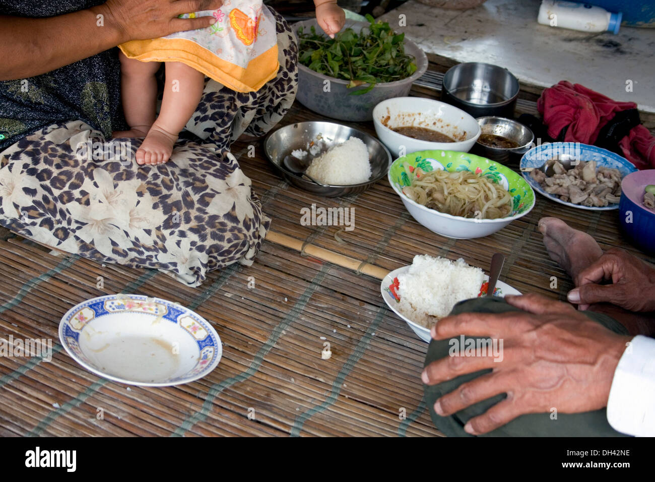 A family is eating lunch underneath their wooden home near a large ...