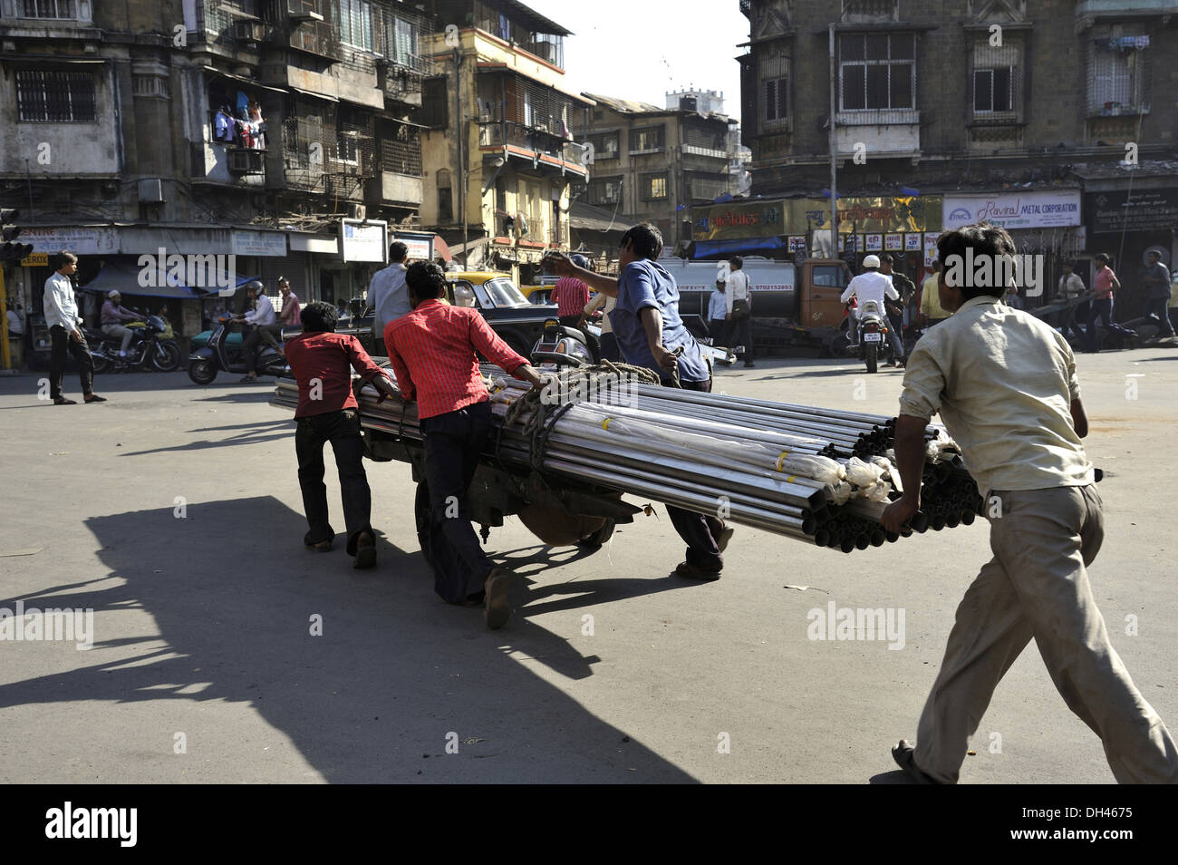 men pushing hand cart with metal pipes at Mumbai Maharashtra India ...