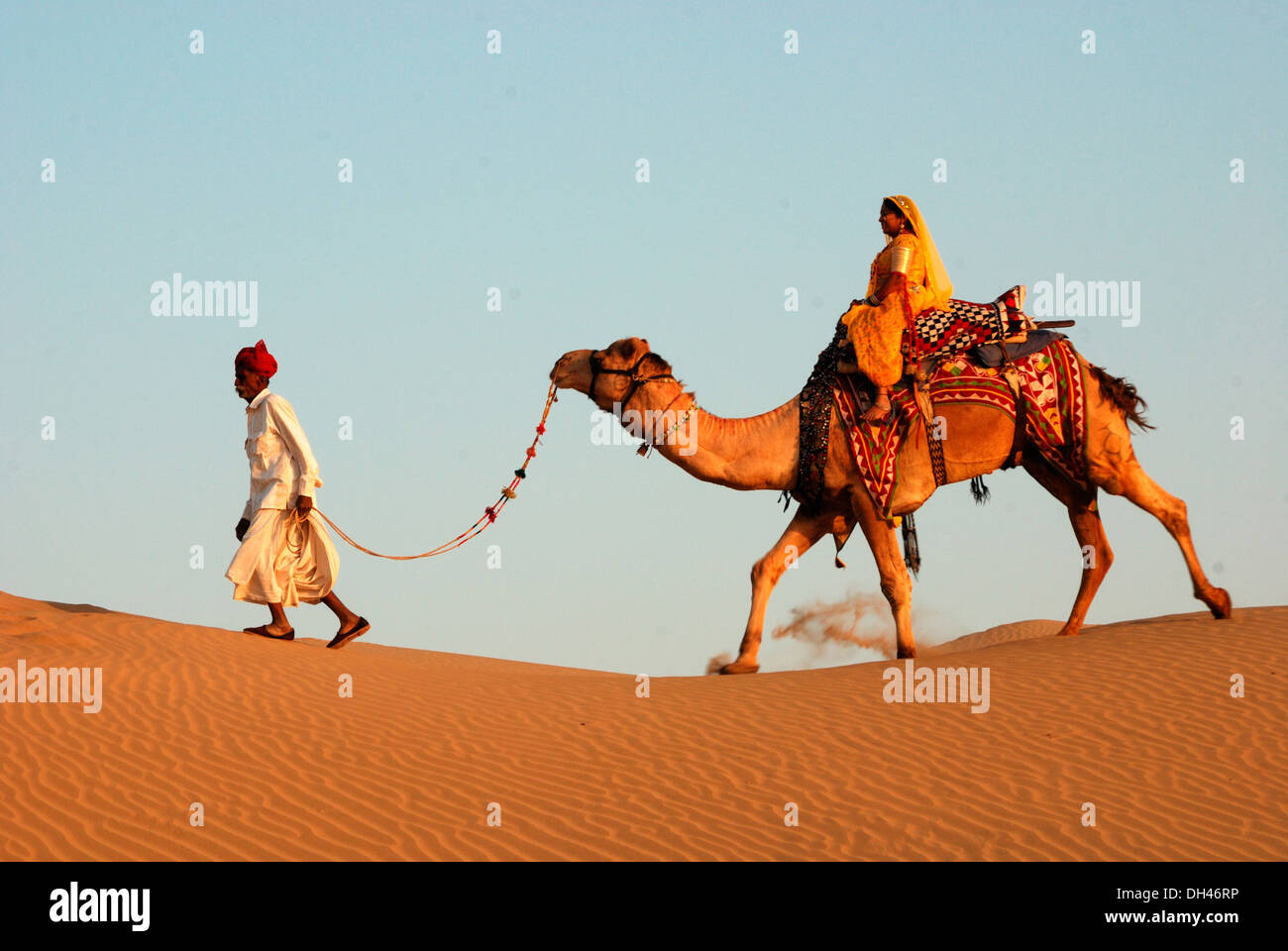 Man leading camel in desert with women sitting on top Jaisalmer ...