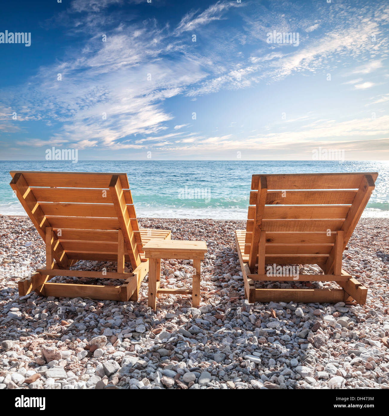 Two wooden sun loungers stand on the Adriatic Sea coast under dramatic ...