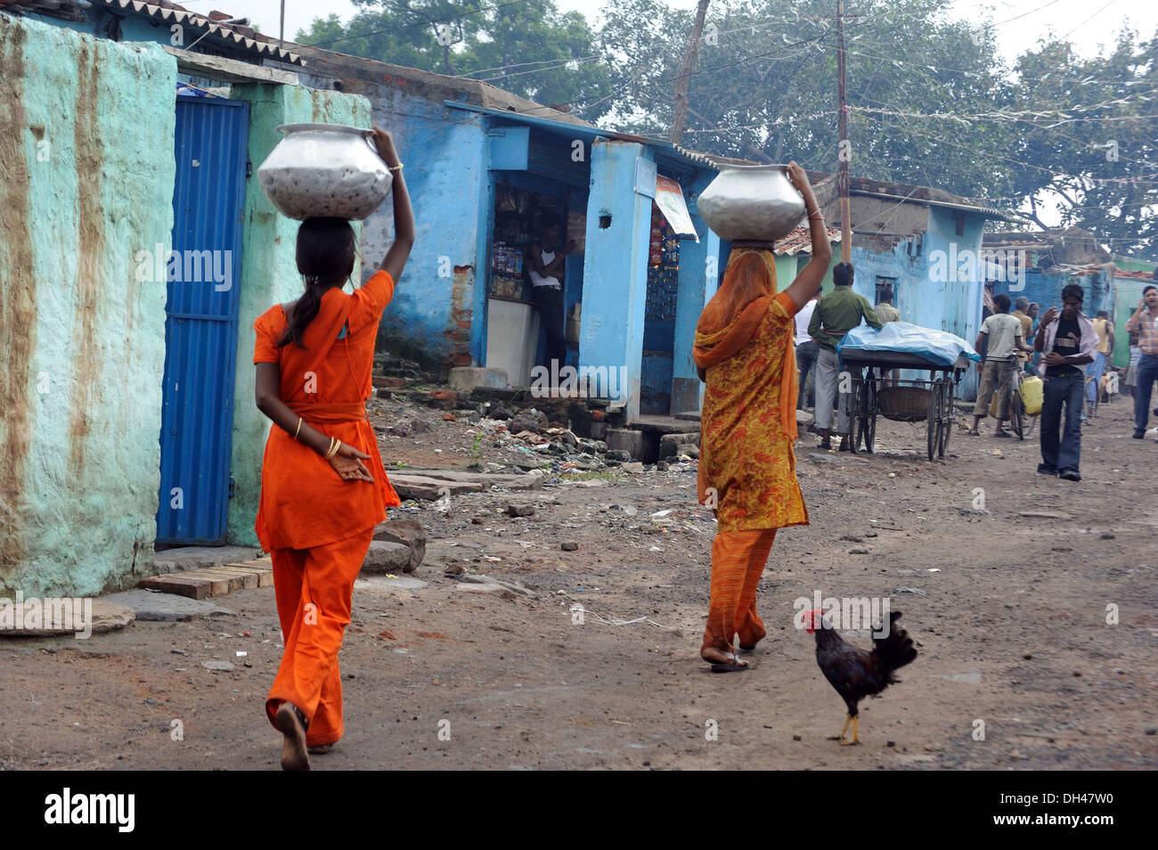 indian woman balancing aluminium water pots on their heads in small ...