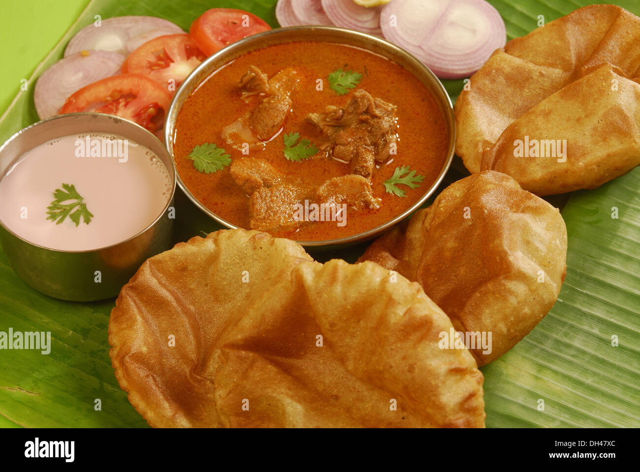 Indian mutton curry with fried puri tomato onion salad milk on green ...
