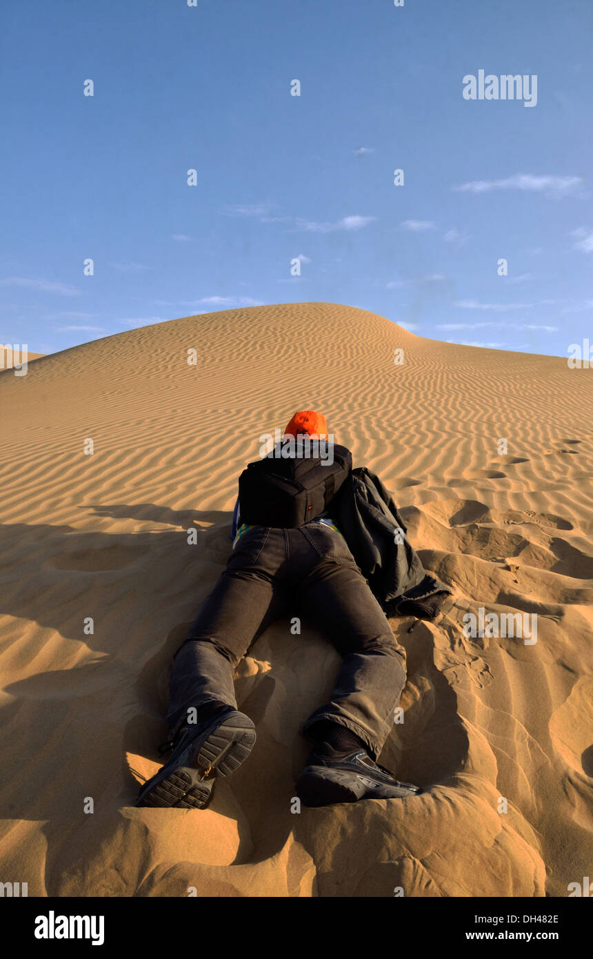 Photographer shooting desert landscape lying on desert sand dune ...