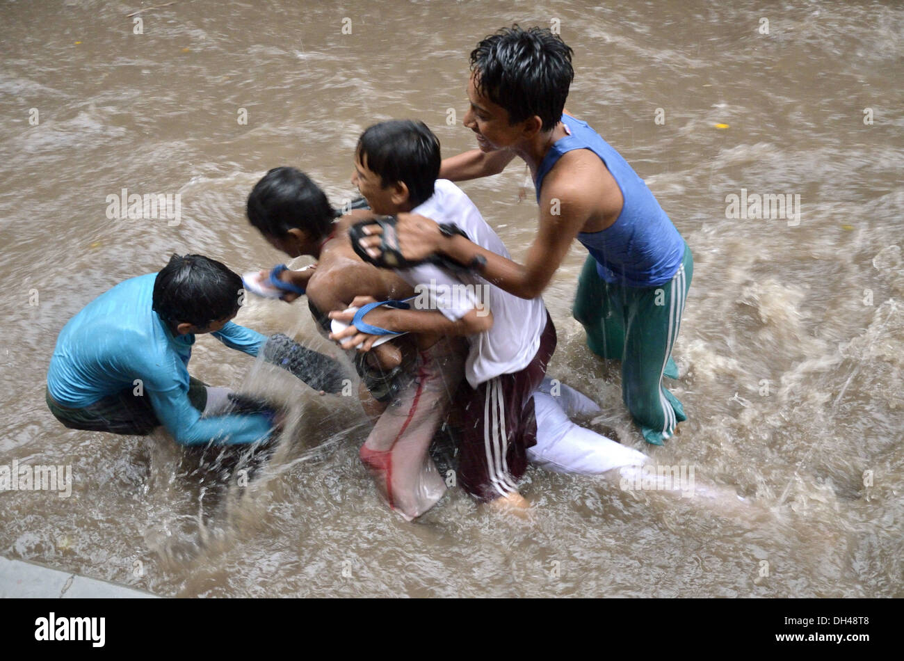 boys playing in flowing monsoon rain water on streets of Jodhpur ...