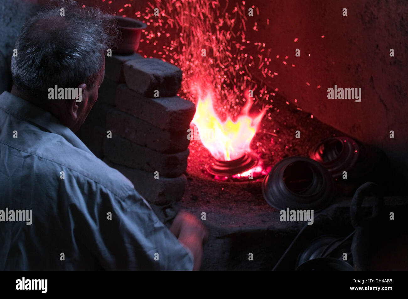 Man heating copper vessel in burning kiln , Pune Maharashtra India Asia ...