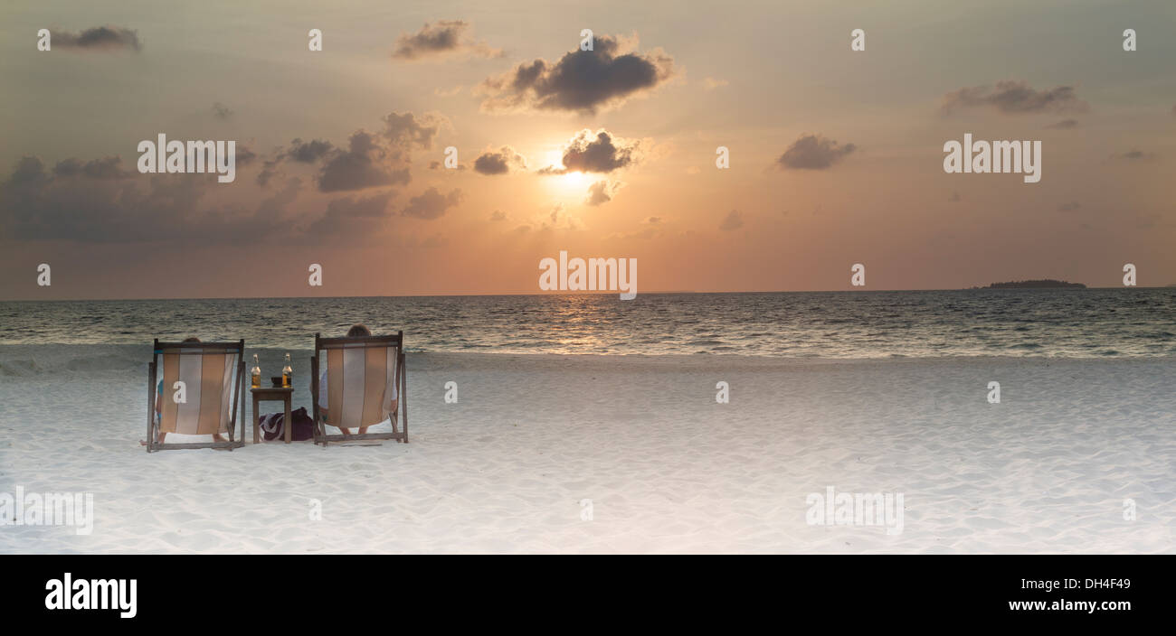 Two people relaxing at sunset on a beach in the Maldives Stock Photo ...
