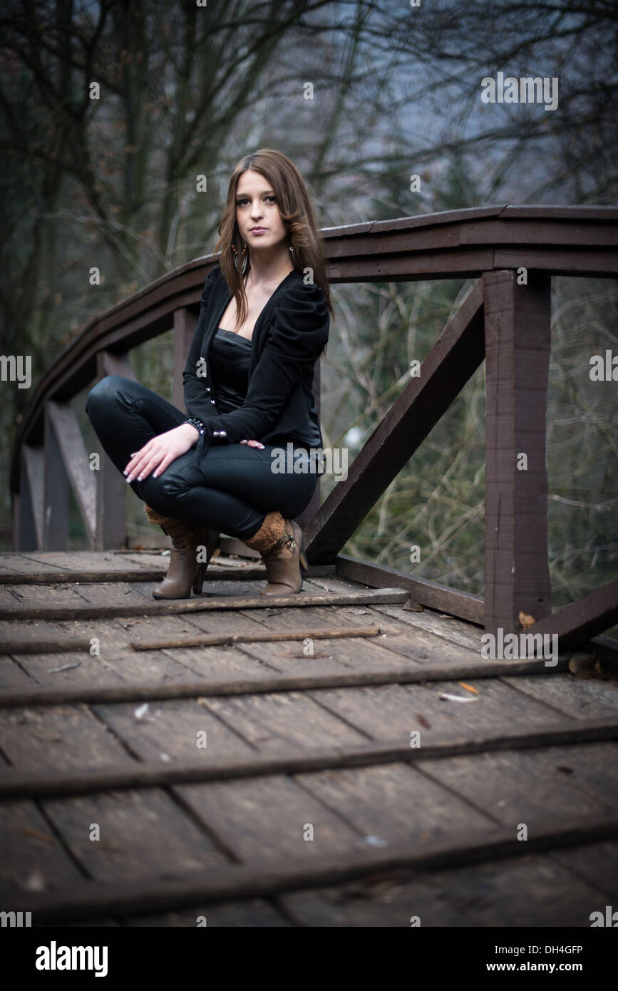 young woman crouch at bridge Stock Photo - Alamy