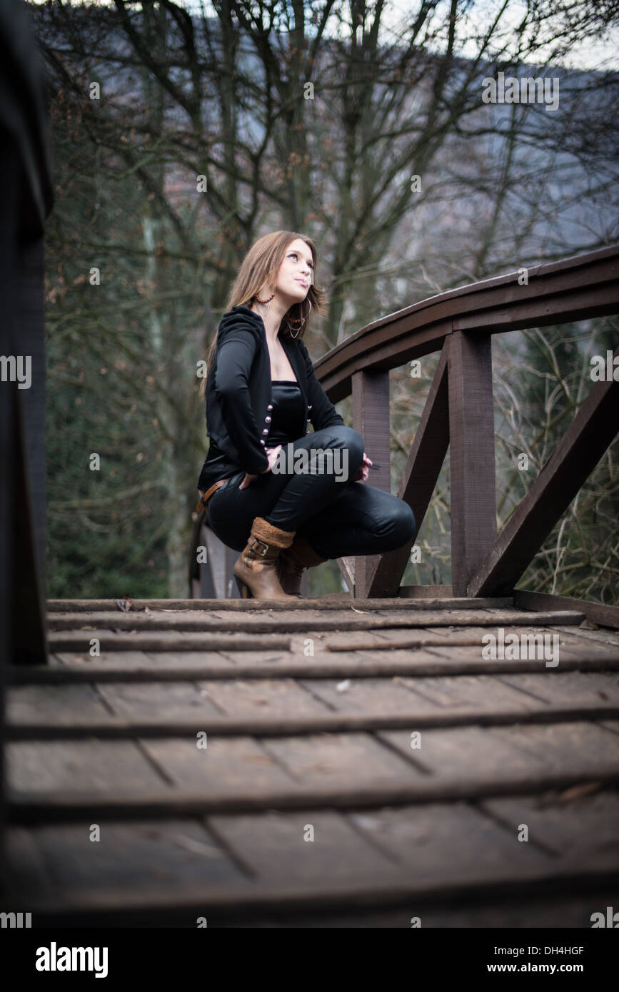 young woman crouch at bridge Stock Photo - Alamy
