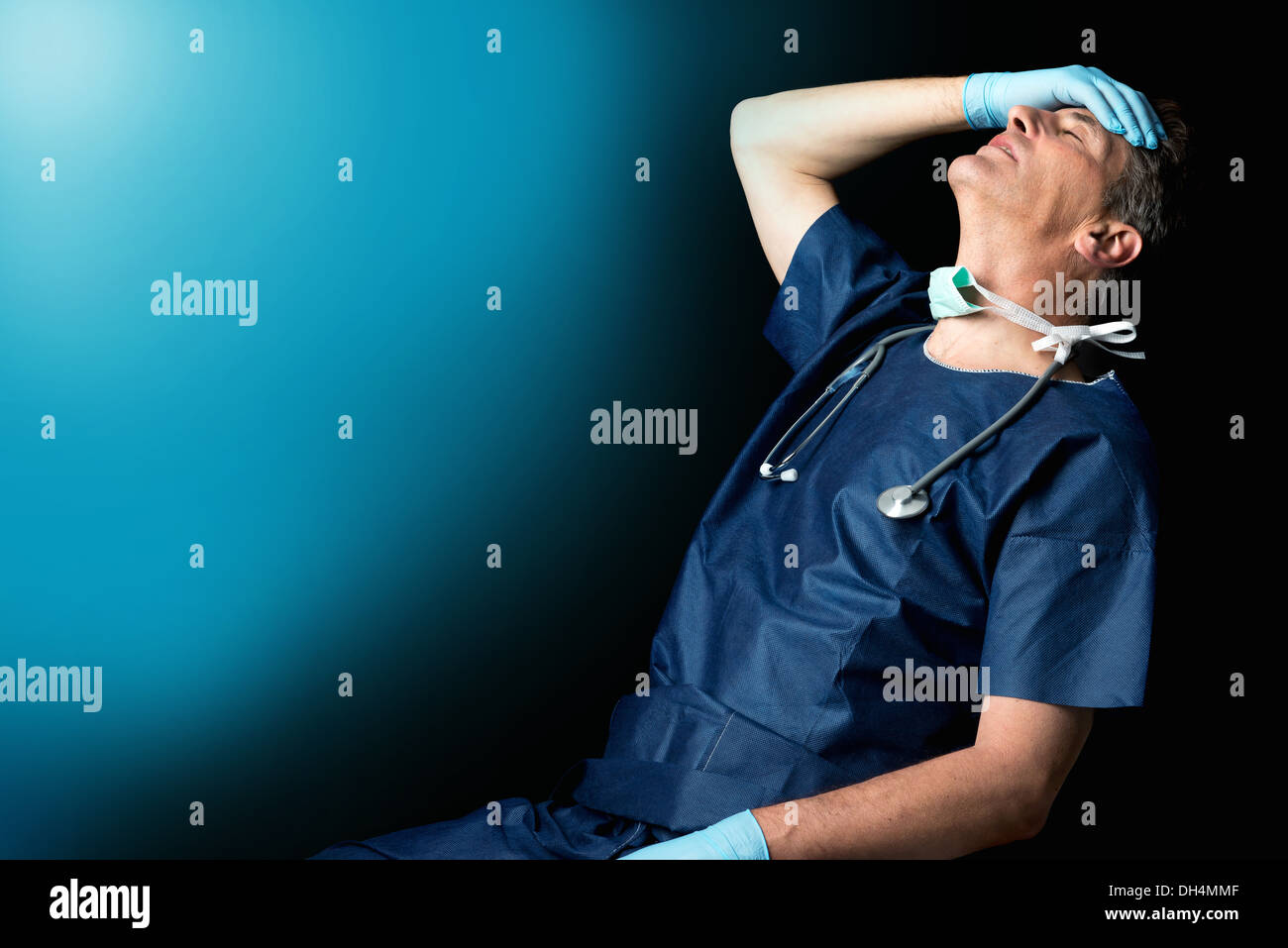 Tired doctor in uniform in a dark background Stock Photo - Alamy
