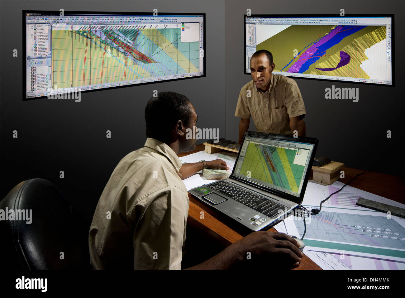 Exploration geologists discussing cross section showing stratigraphy of ...