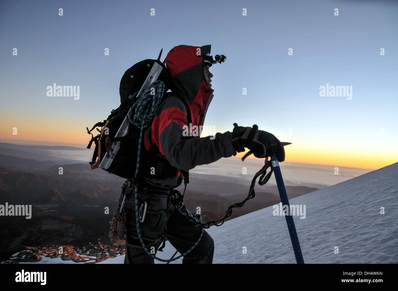 An alpine mountain climber ascends a glacier in the early morning light ...