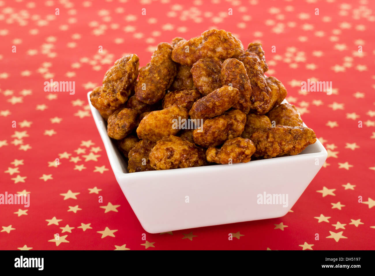 Burnt almonds in white dish on red background Stock Photo - Alamy