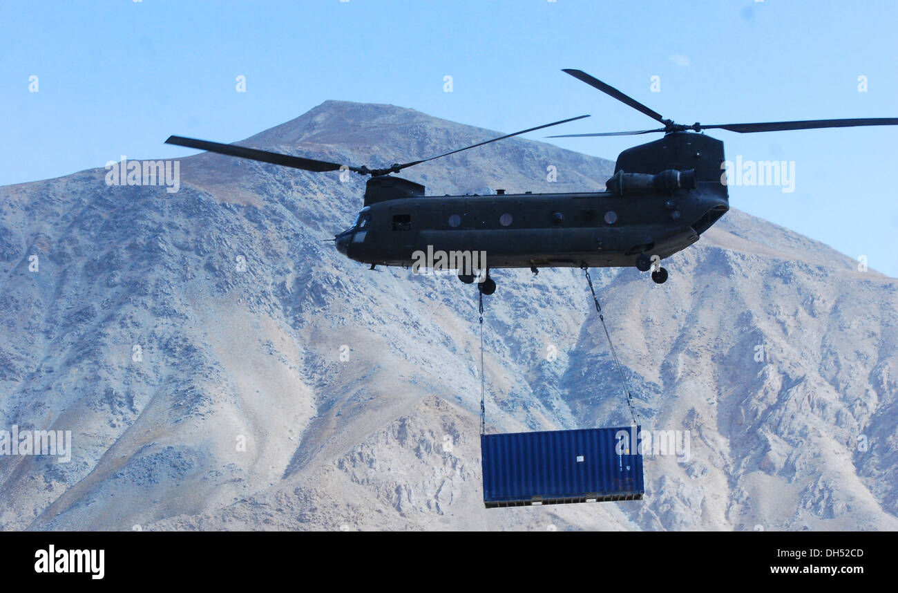 A 10th Combat Aviation Brigade CH-47 Chinook helicopter sling loads a shipping container beneath ...