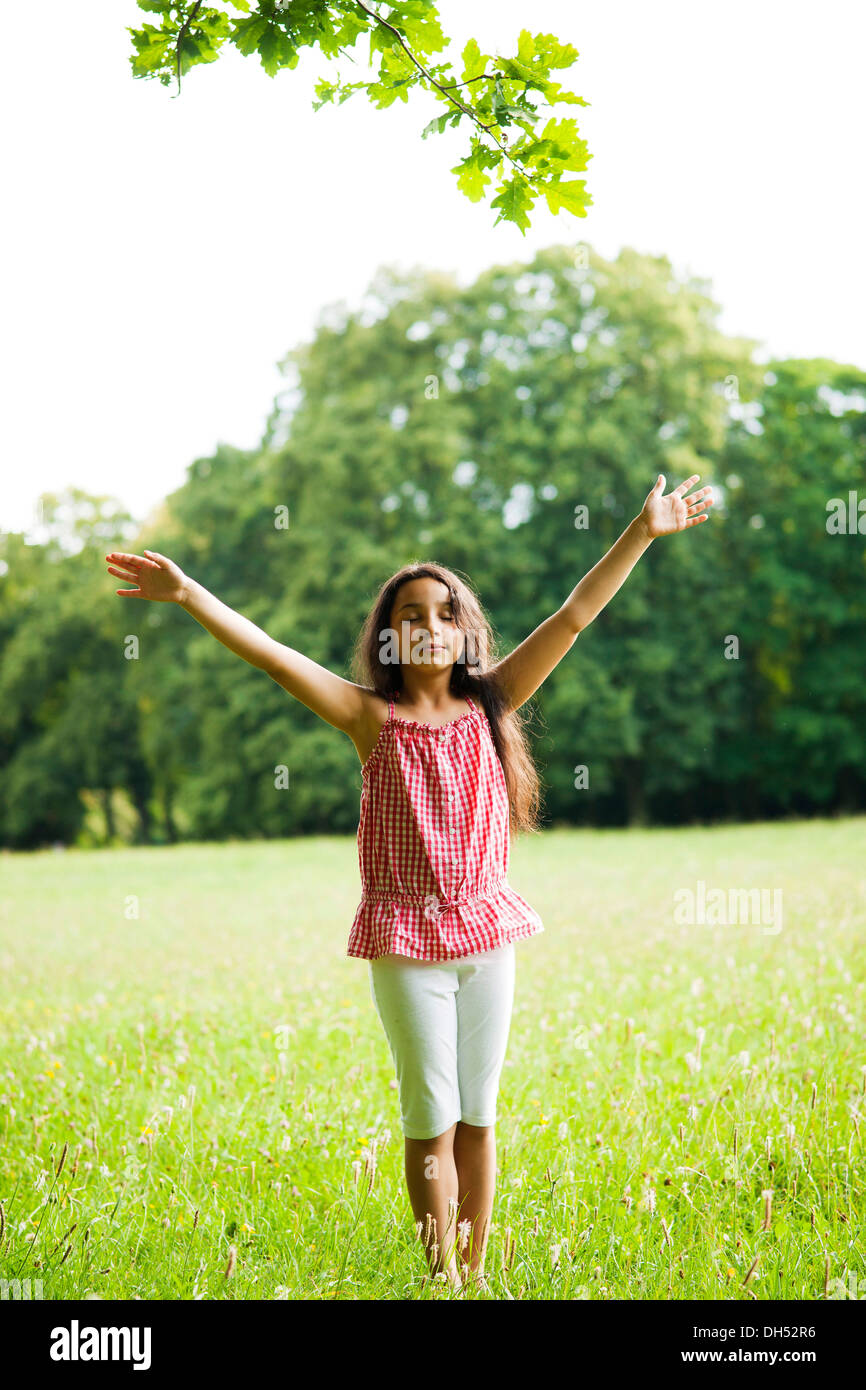 Girl standing in a meadow throwing her arms up into the air Stock Photo ...