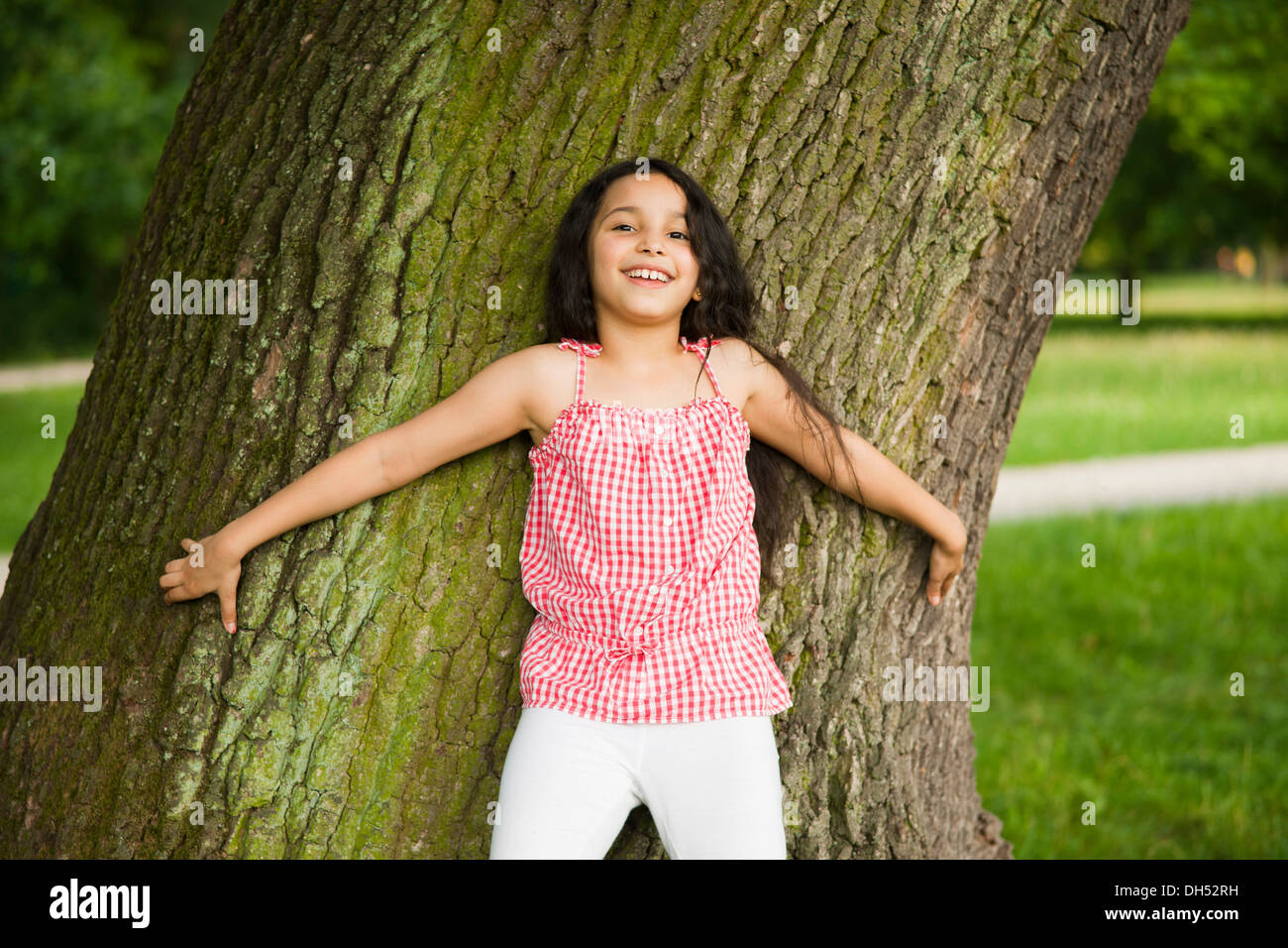 Smiling girl hugging a tree Stock Photo - Alamy