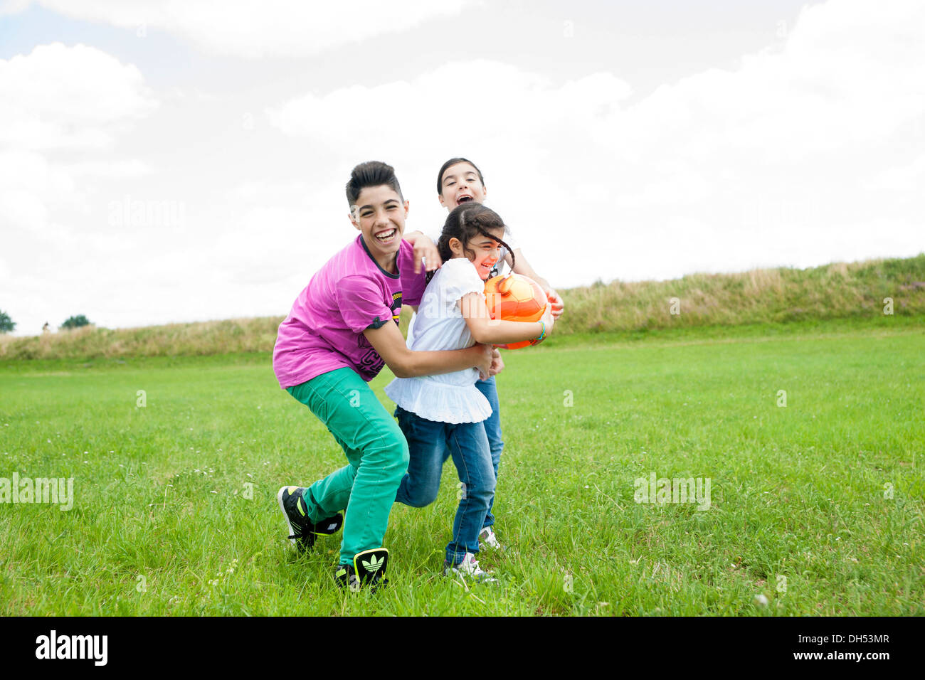 Three children playing ball on a meadow Stock Photo - Alamy