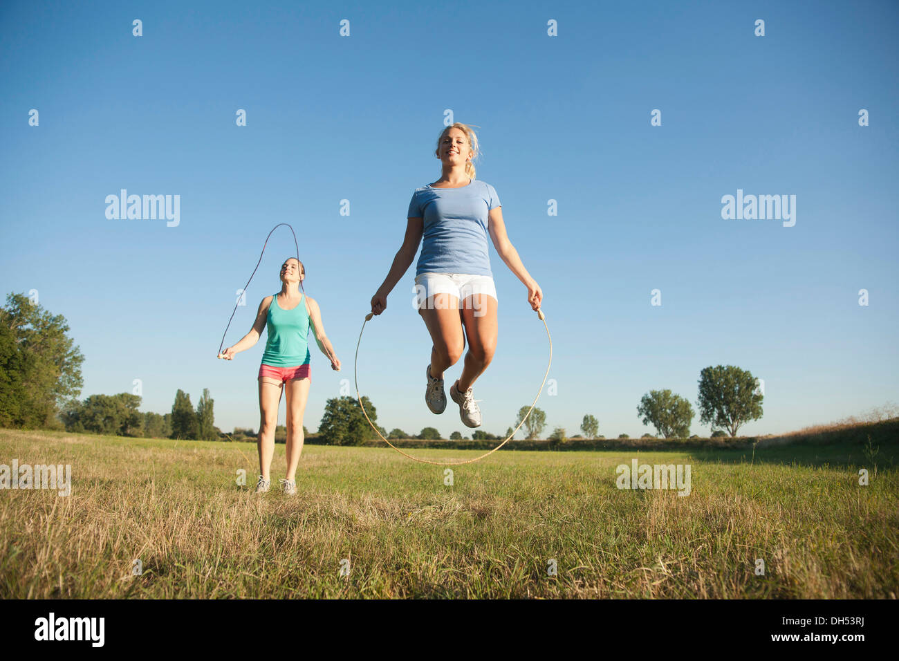 Two young women jumping rope in a meadow Stock Photo - Alamy