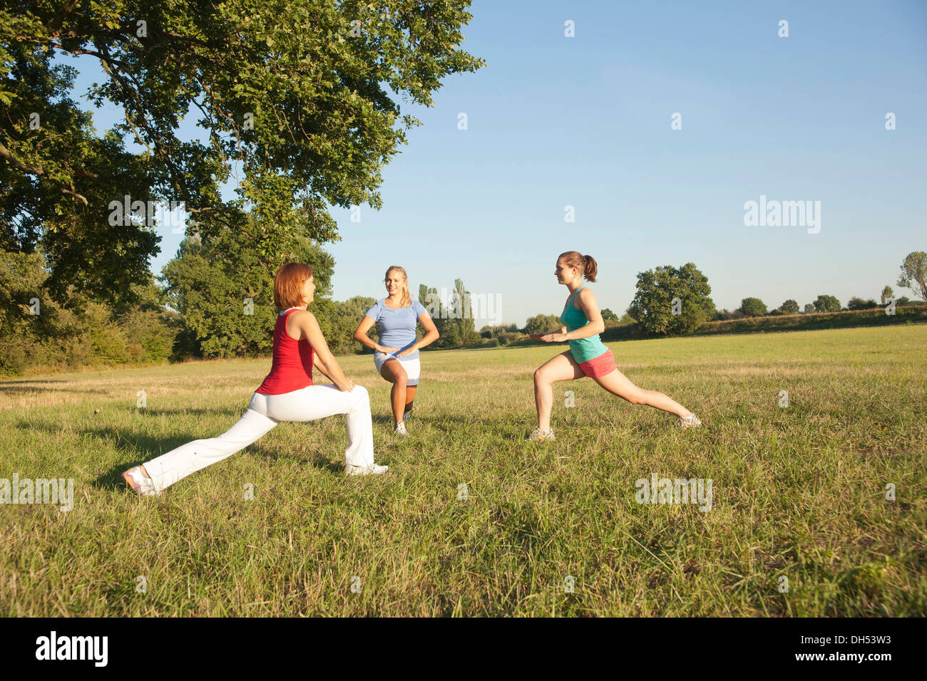 Three young women doing gymnastics exercises together in a meadow Stock ...