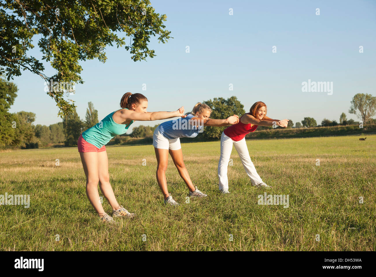 Three young women doing gymnastics exercises together in a meadow Stock ...