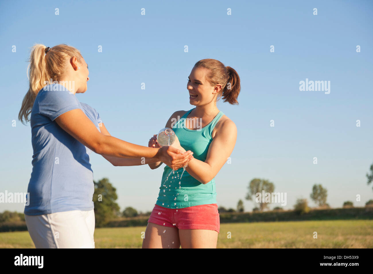 Two young women having fun with a bottle of water during a drink break ...